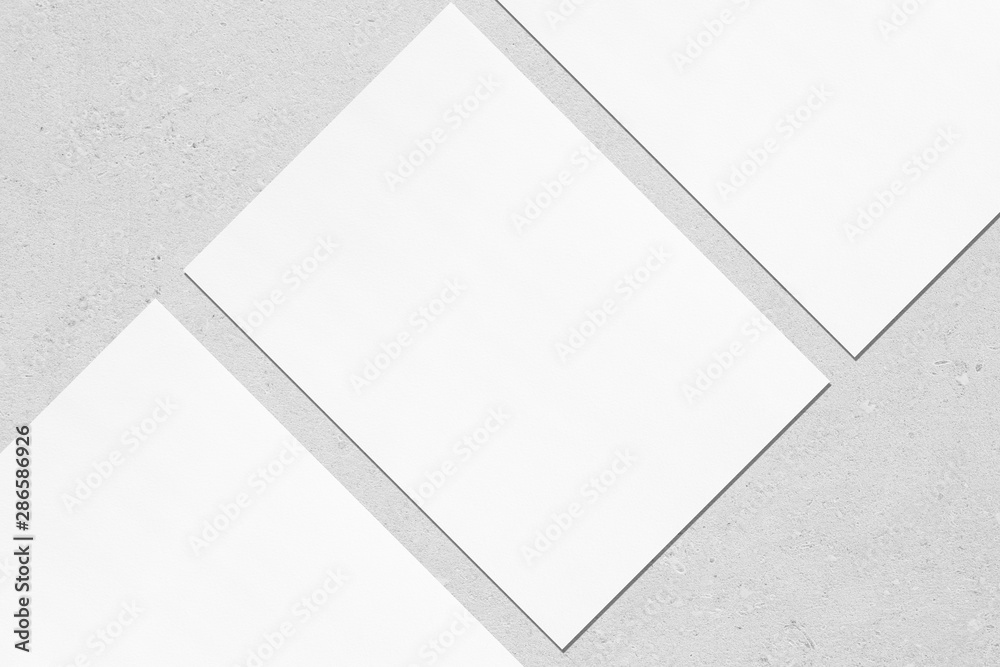 Closeup of three empty white rectangle poster mockups lying diagonally ...