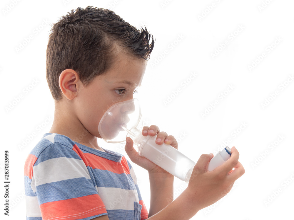 portrait of a 6 year old young boy using an inhaler mask for treating ...