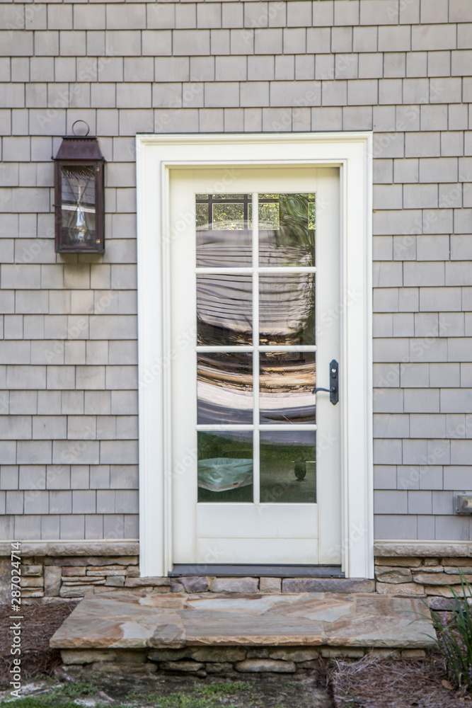 cape cod style home with white wood door at back entrance. Door has ...