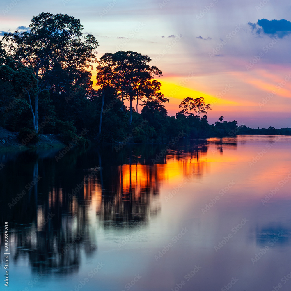 Reflection of a sunset by a lagoon inside the Amazon Rainforest Basin ...