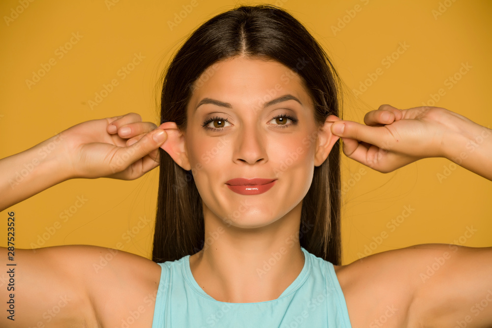 Beautiful young smiling woman pulling her ears with her fingers on ...