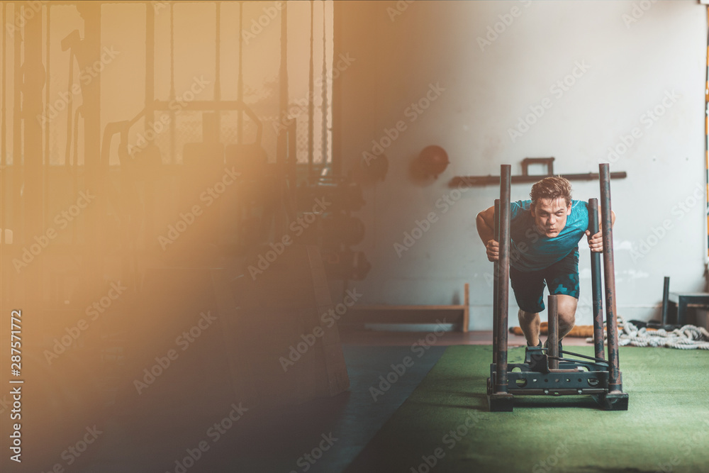 Full-length portrait of strong young man pulling a heavy trainer as a ...