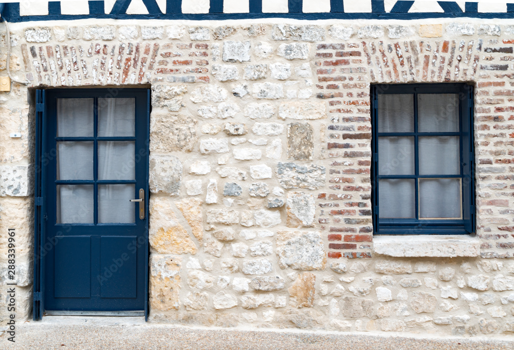 typical stone house facade in Normandy in France with blue doors and ...