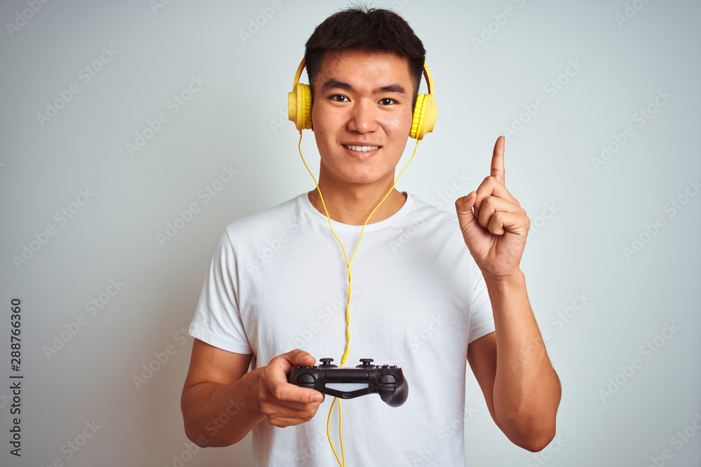 Young asian chinese gamer man playing video game standing over isolated ...