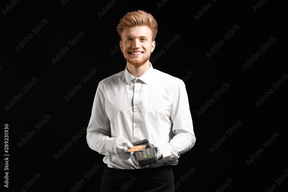 Handsome waiter with payment terminal on dark background Stock Photo ...