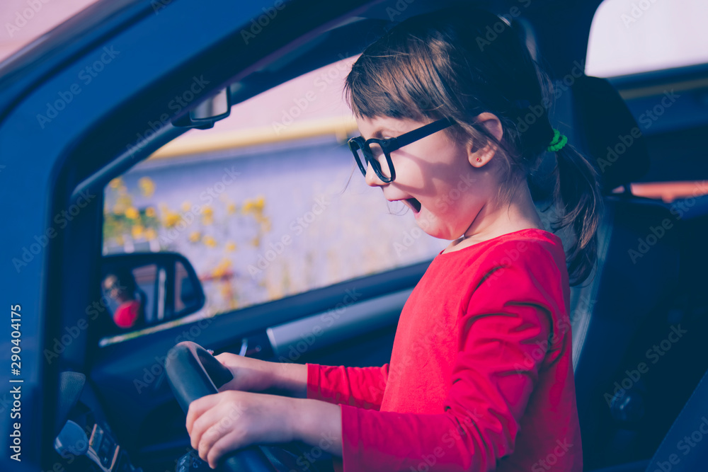 Dangers and risks of underage driving. A little child girl driving a ...