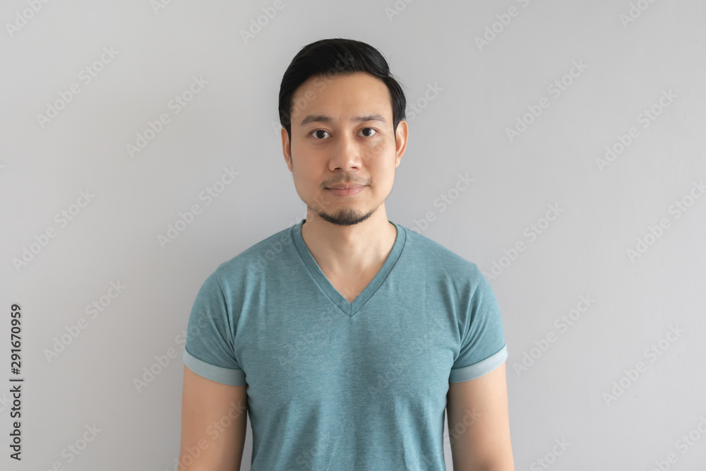 Normal straight face portrait of man in blue t-shirt on grey background ...