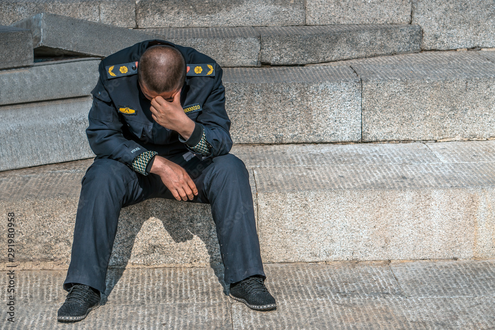 Sad policeman is sitting on the floor with his had down, he lost his ...