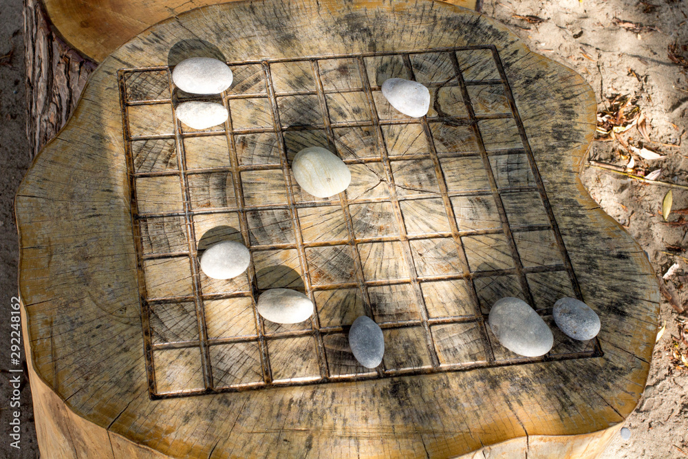 outdoor chess board with stone game pieces on a beach made from a tree ...