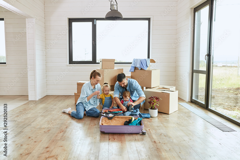 family, man, woman and two girls, sit on floor, near suitcase and take ...