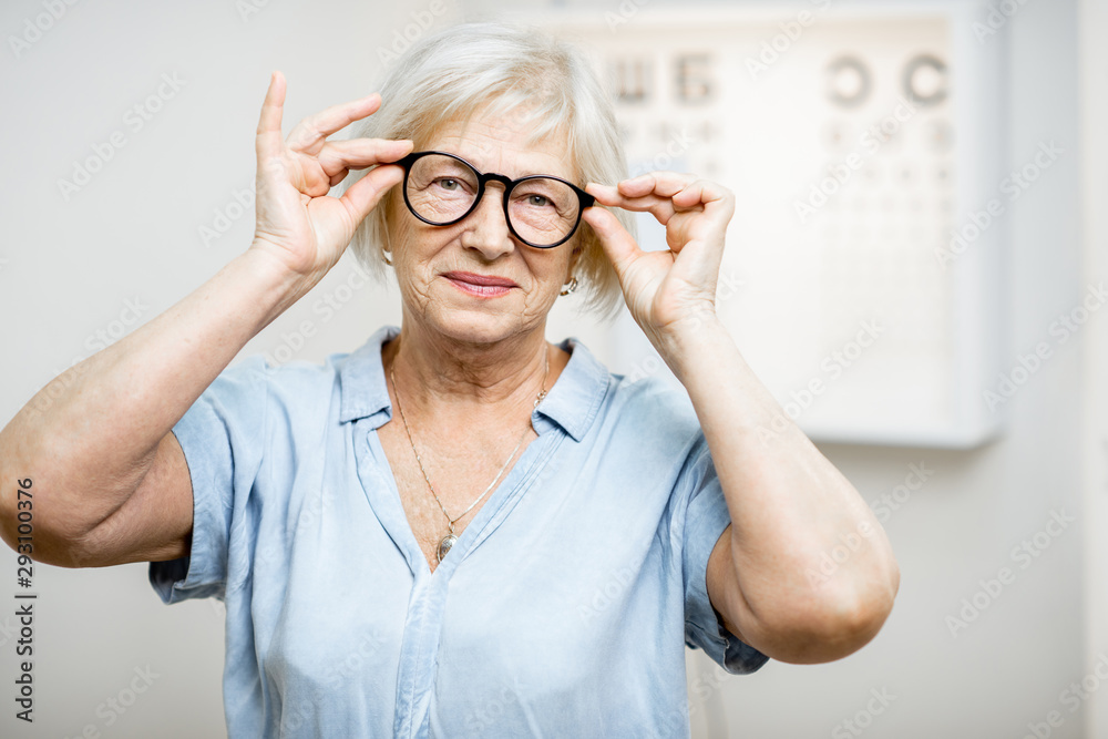 Portrait of a happy senior woman wearing eyeglasses in front of eye ...