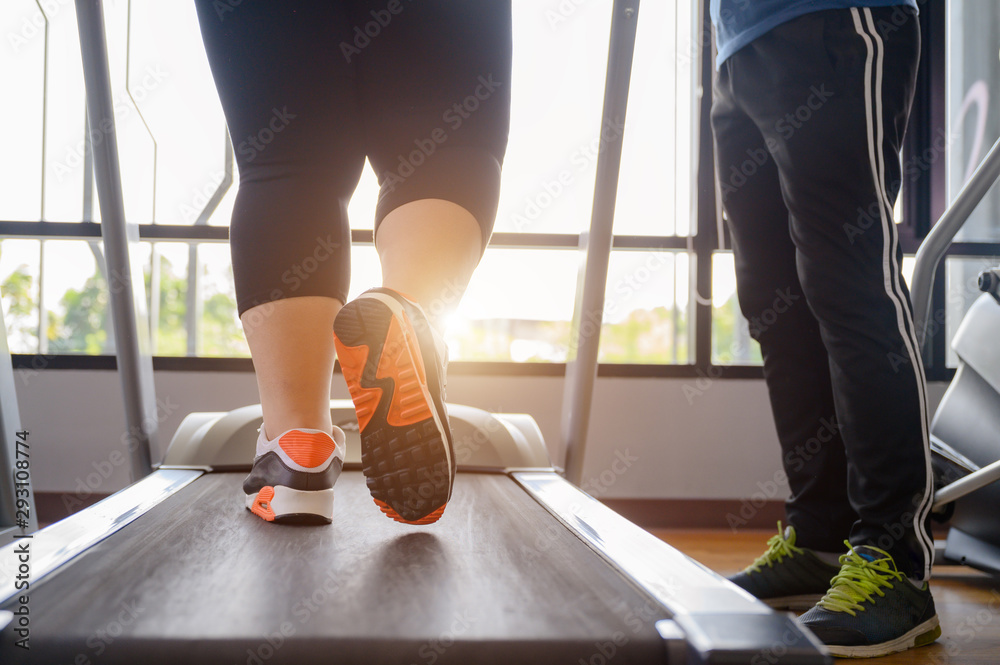 leg of fat woman being run or jog on belt of treadmill machine, workout ...