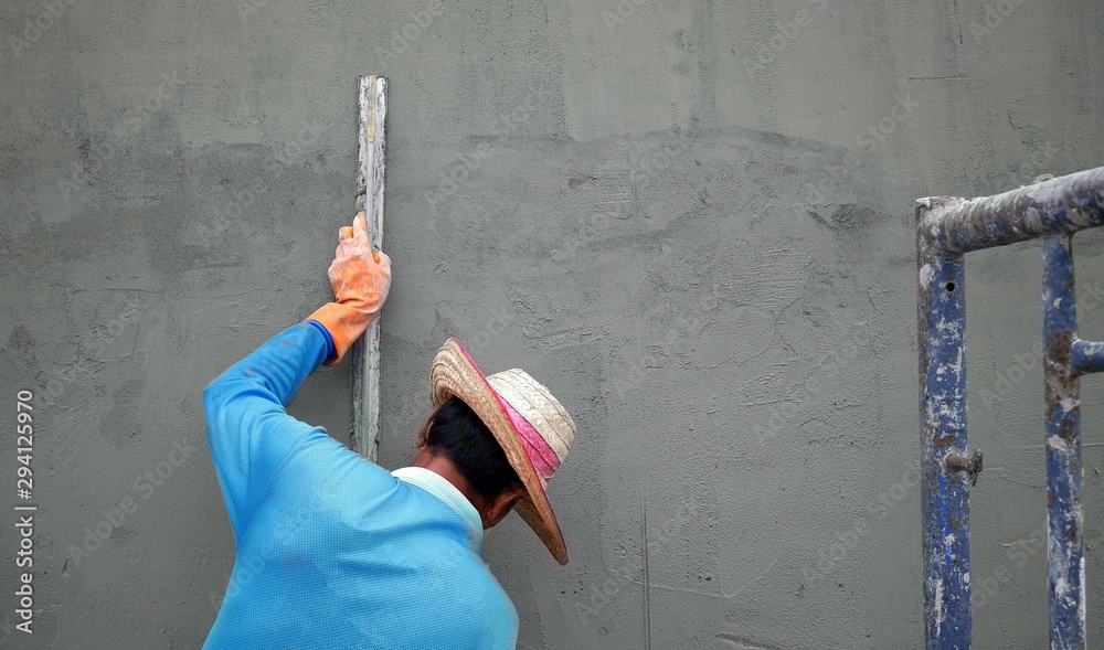 Rear view of Asian builder man using triangle trowel to plastering ...