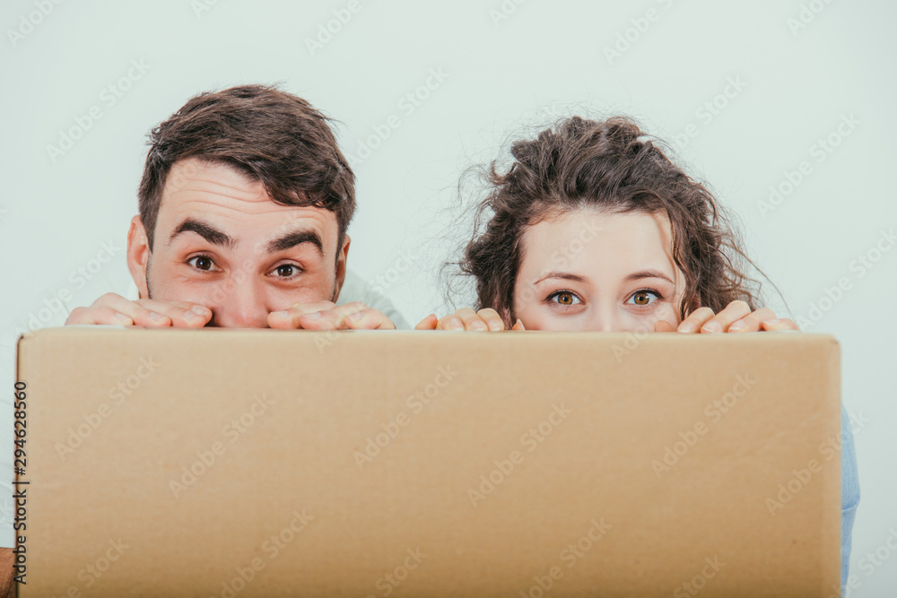 Funny wife and husband hiding behind the big carton box, together ...