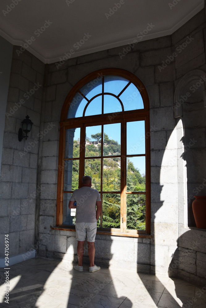 Tourist - a man stands and look at the huge glass window of the castle ...