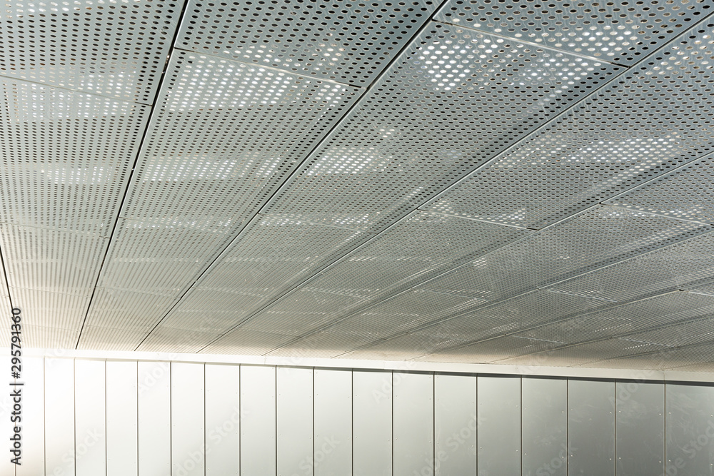 Diagonal view of metall grilles and round holes in metal ceiling ...