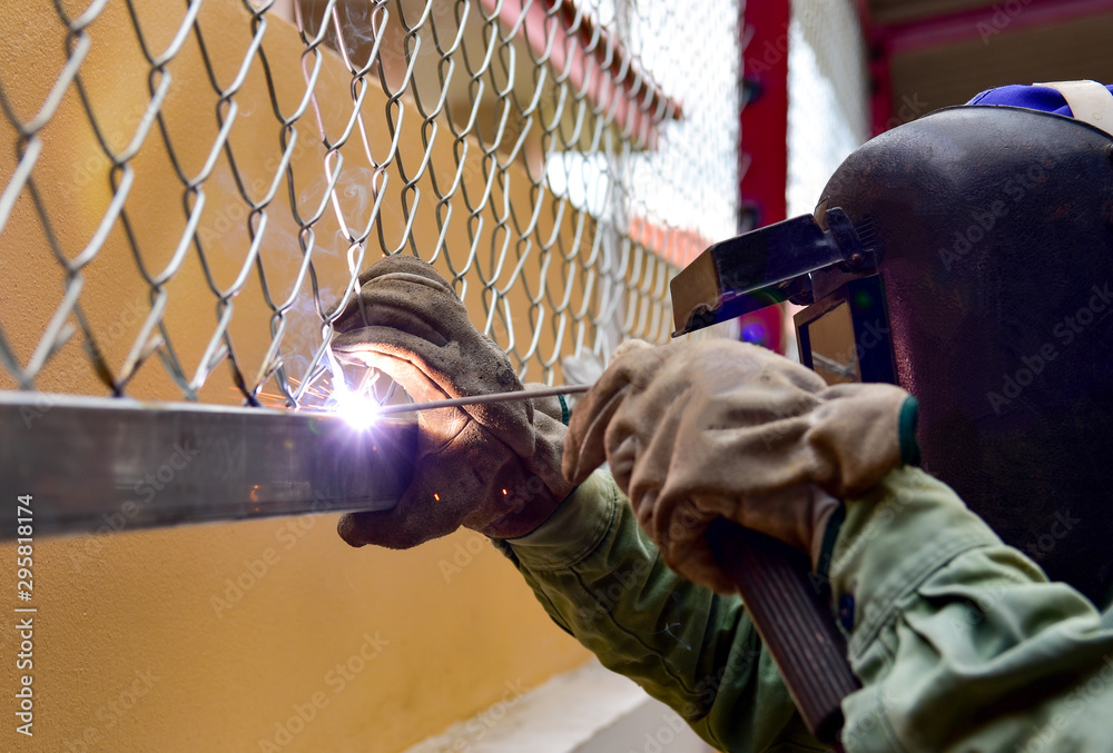 Welder is welding the steel wire mesh to steel beam by process shielded ...