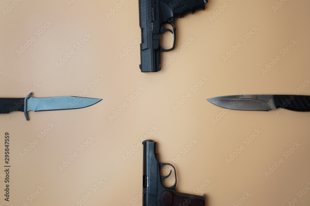 Firearms laid out along a circle. Three guns pistols, army knives close ...