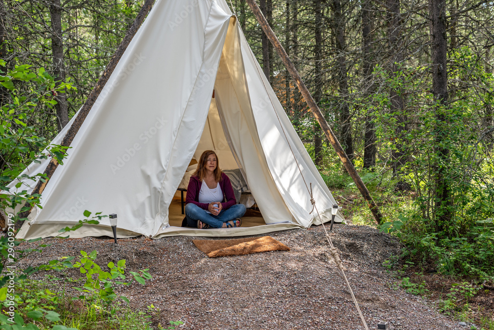 glamping trip - woman sitting and relaxing in canvas teepee on campsite ...