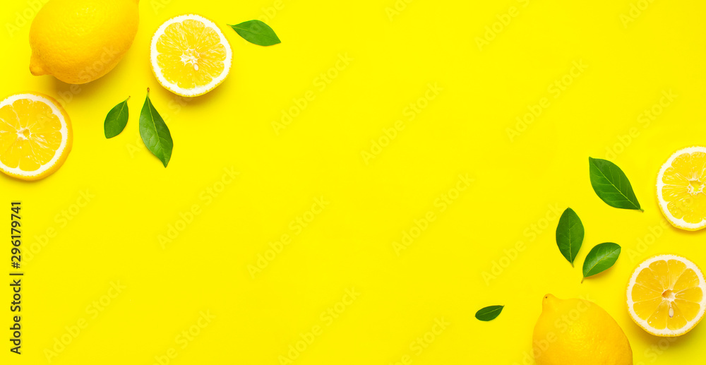 Creative background with fresh lemons and green leaves on bright yellow ...