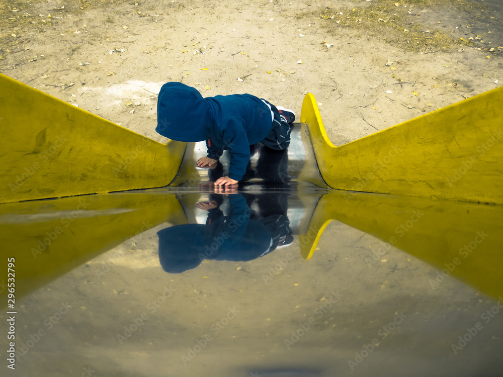 Little boy on children's slide with yellow sides and a shiny metal ...