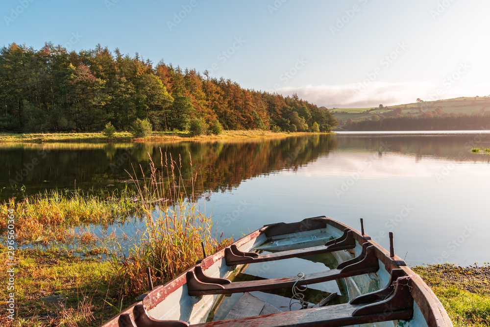 Rowing boat half filled with rain water on the shore of the lake on a ...