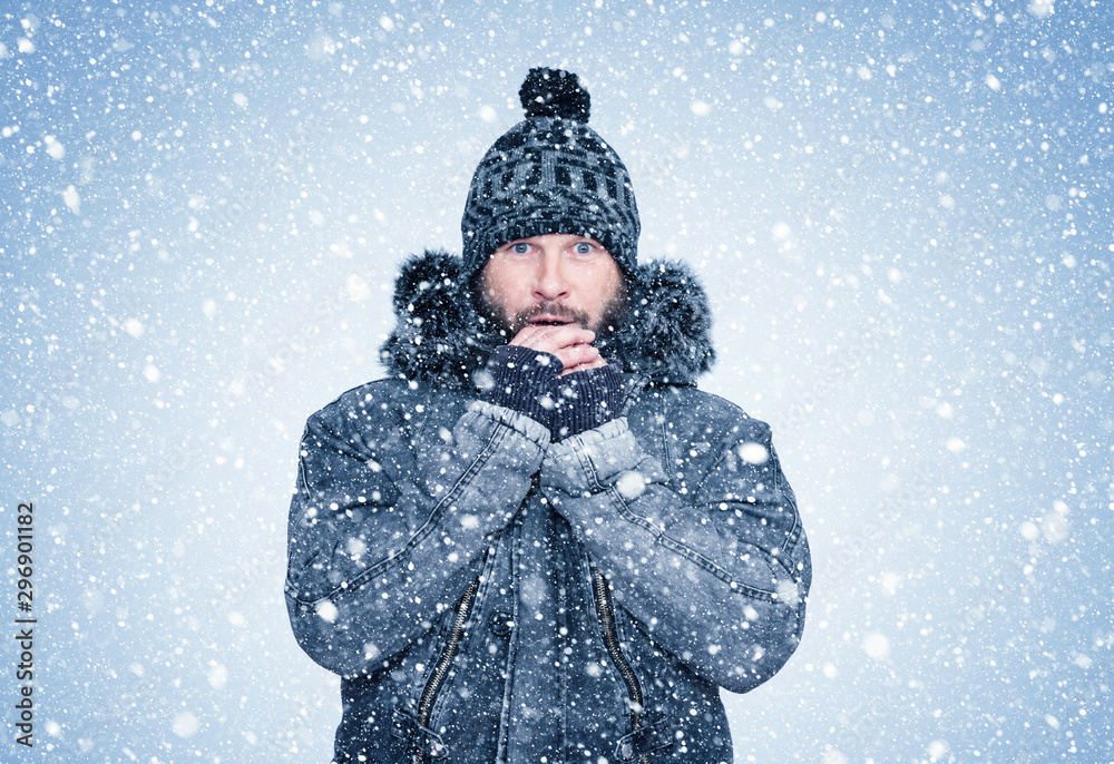 Frozen bearded man in winter clothes warms his hands, cold, snow, frost ...