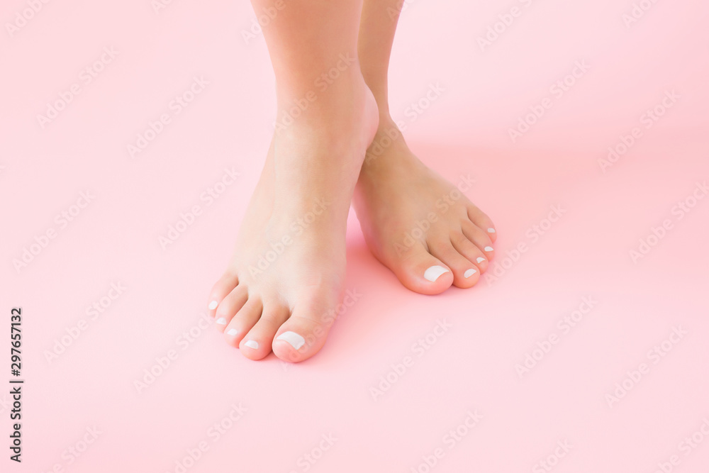 Young, perfect, groomed woman's feet on pastel pink background. Care ...