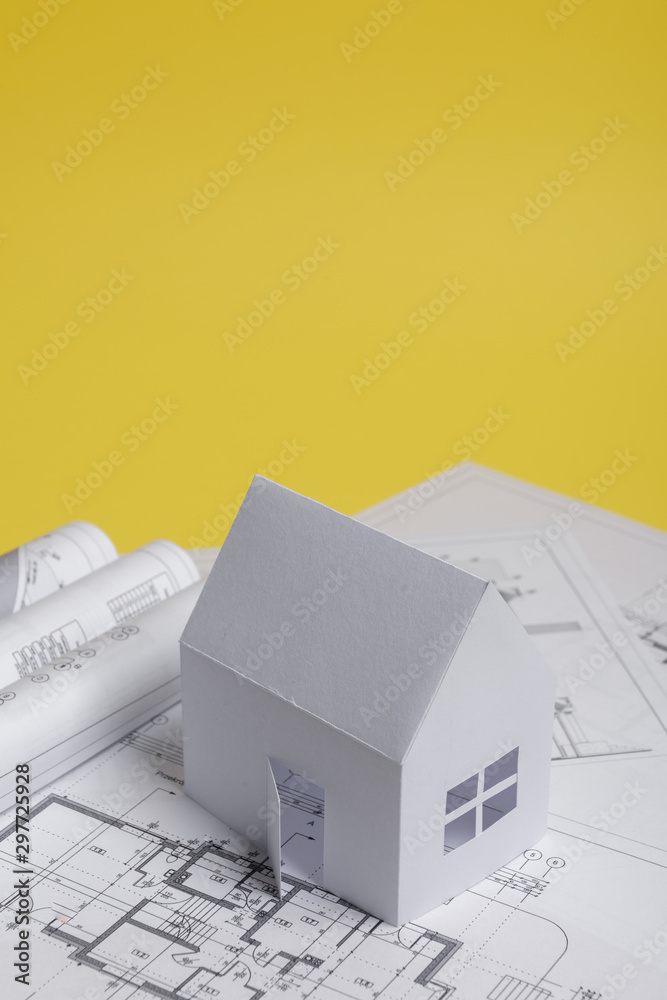 White family paper house, house projects plan and blueprints on yellow ...