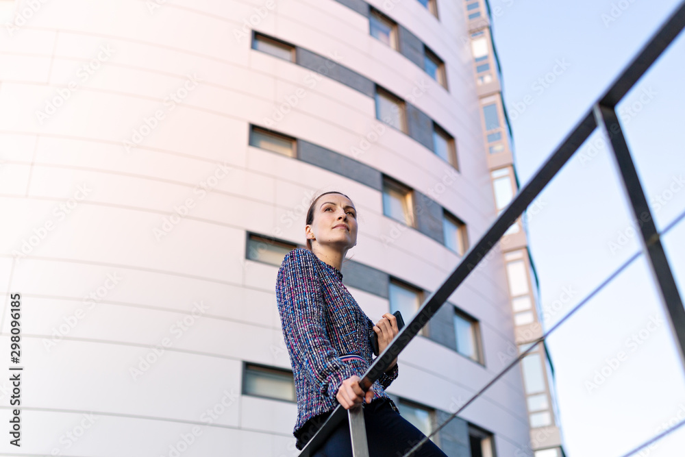 Low angle of serious female manager in elegant outfit leaning on ...