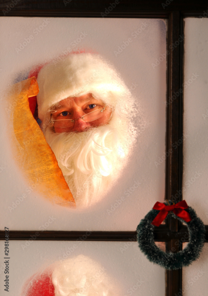 Portrait of Santa Claus seen through a frosted window as he checks his ...