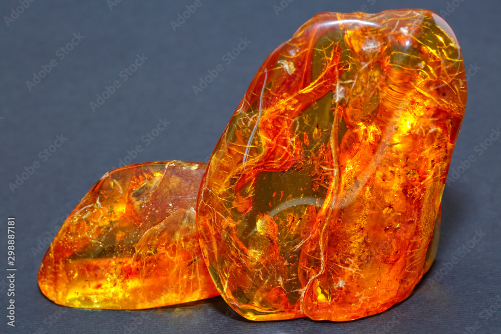 Amber. Two yellow-red polished pieces of natural amber on a blue ...