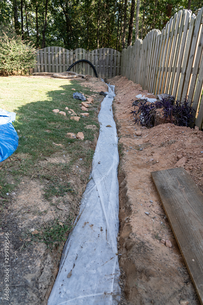 Fabric covers drainage rock and pipe to keep a French drain clear of ...