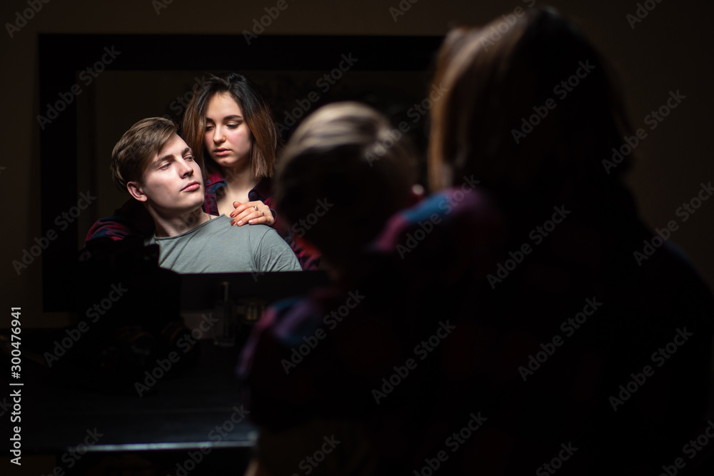 Reflection of a man and a girl in the mirror. The girl puts her arm ...