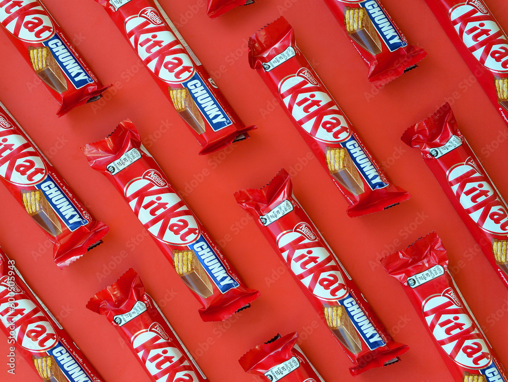 Kit Kat chocolate bars in red wrapping lies on yellow background is now ...