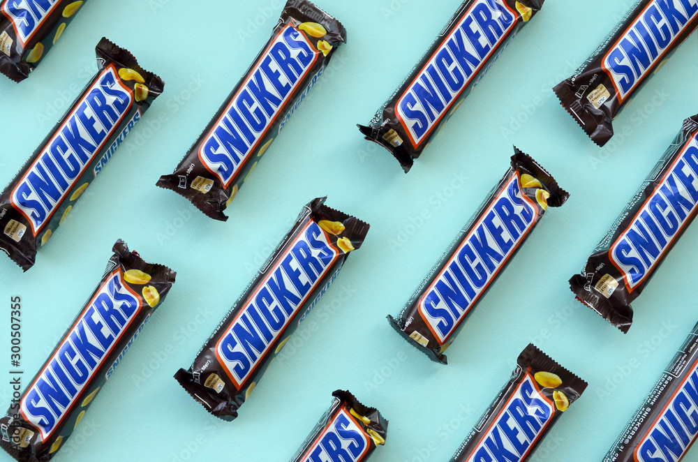 Many Snickers chocolate bars lies on pastel blue paper. Snickers bars ...