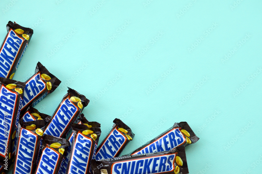 Many Snickers chocolate bars lies on pastel blue paper. Snickers bars ...