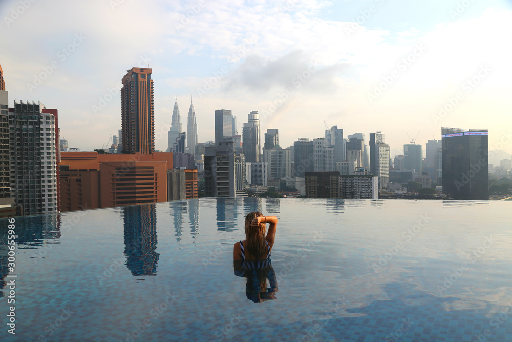 Young happy girl swimming alone in the infinity pool on rooftop in ...