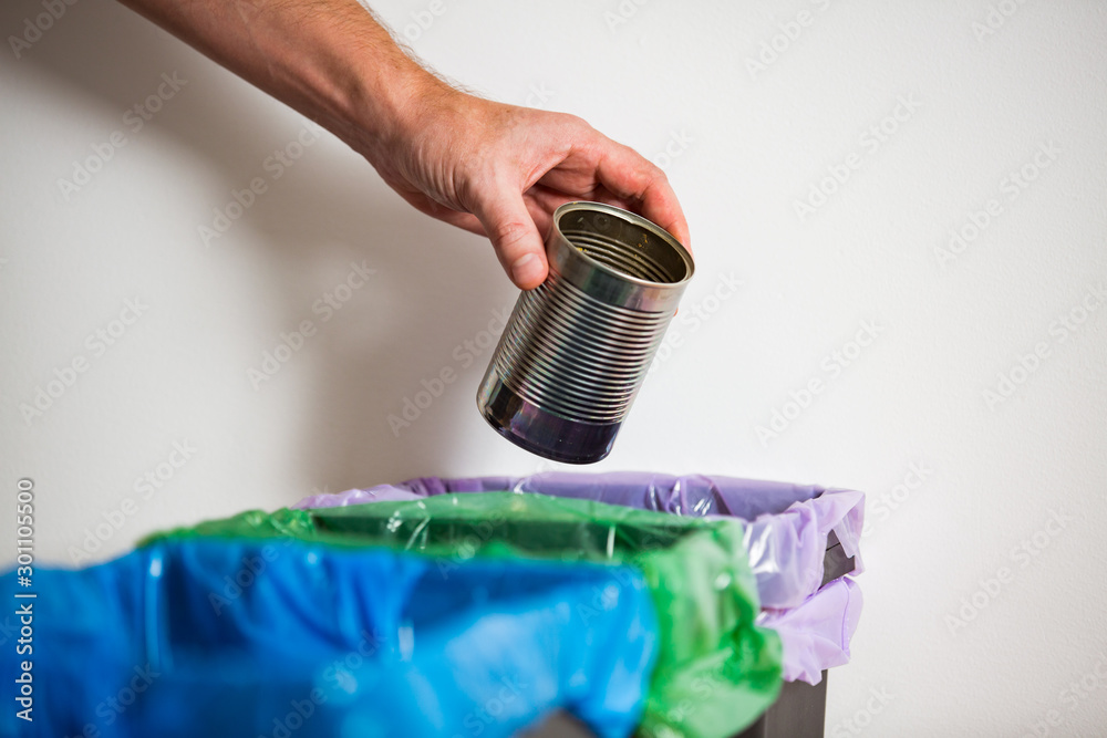 Hand putting tin can into recycling bin. Person in a house kitchen ...