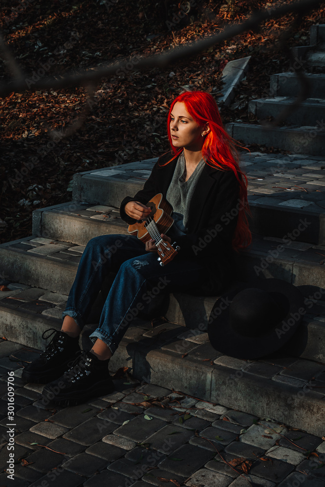 Sexy redhead girl with long hair plays the ukulele. Perfect woman ...