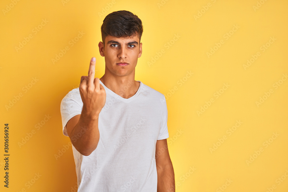 Young indian man wearing white t-shirt standing over isolated yellow ...