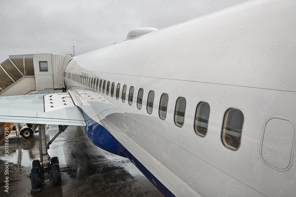 Passenger aircraft fuselage detail at an airport with jet bridge ...