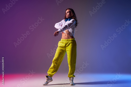 Beautiful young female hip hop dancer with long curly hair, dressed in ...