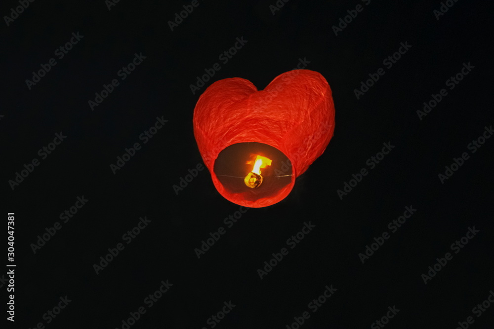 view of red sky lantern shape heart floating in dark sky background ...