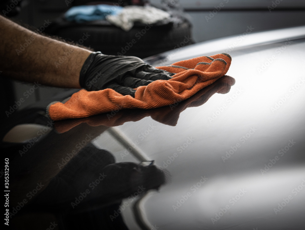 car wash - polishing a car with an orange cloth and a male hand with a ...