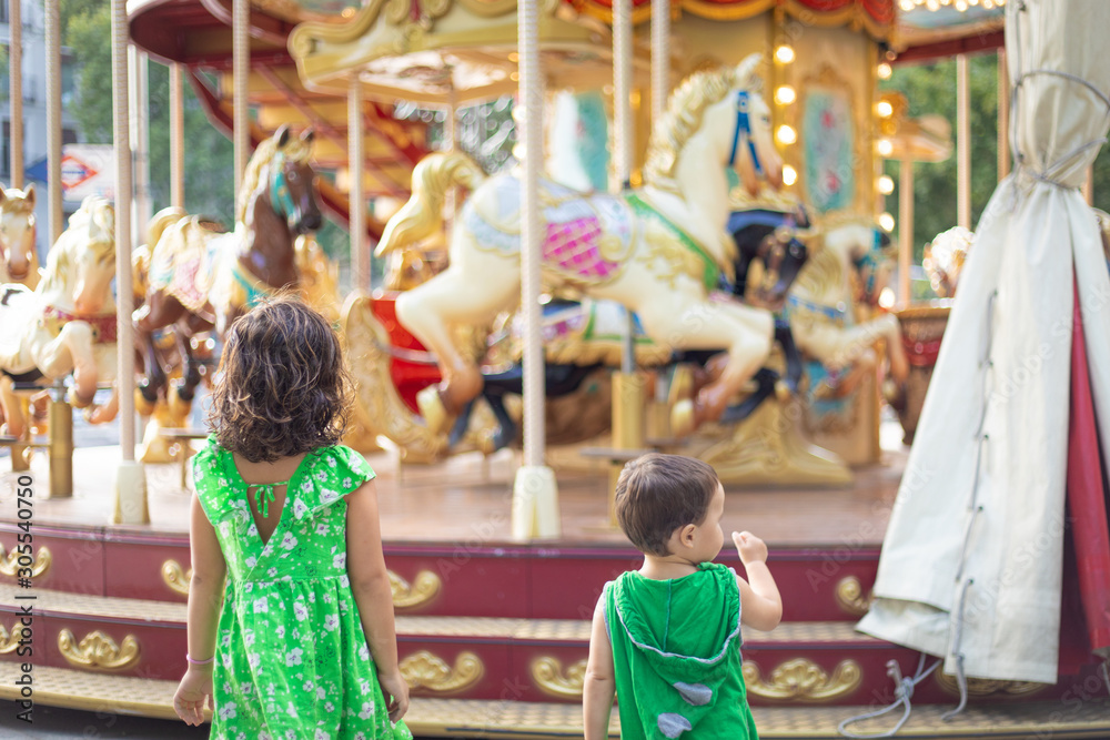 Back view of curious kids in green casual clothes standing and watching ...