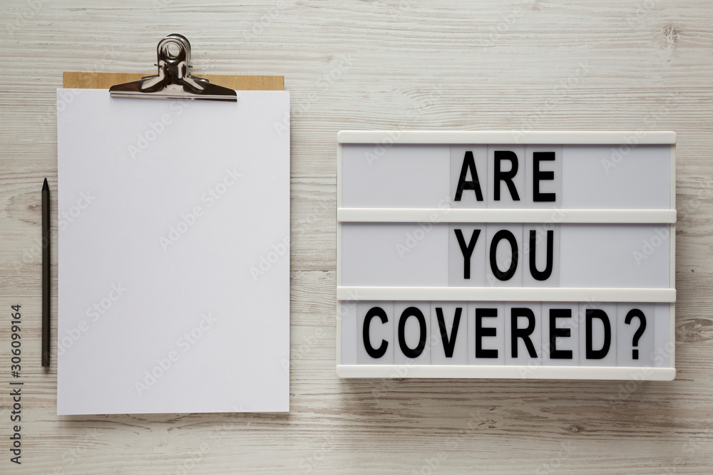 'Are you covered?' words on a lightbox, clipboard with blank sheet of ...