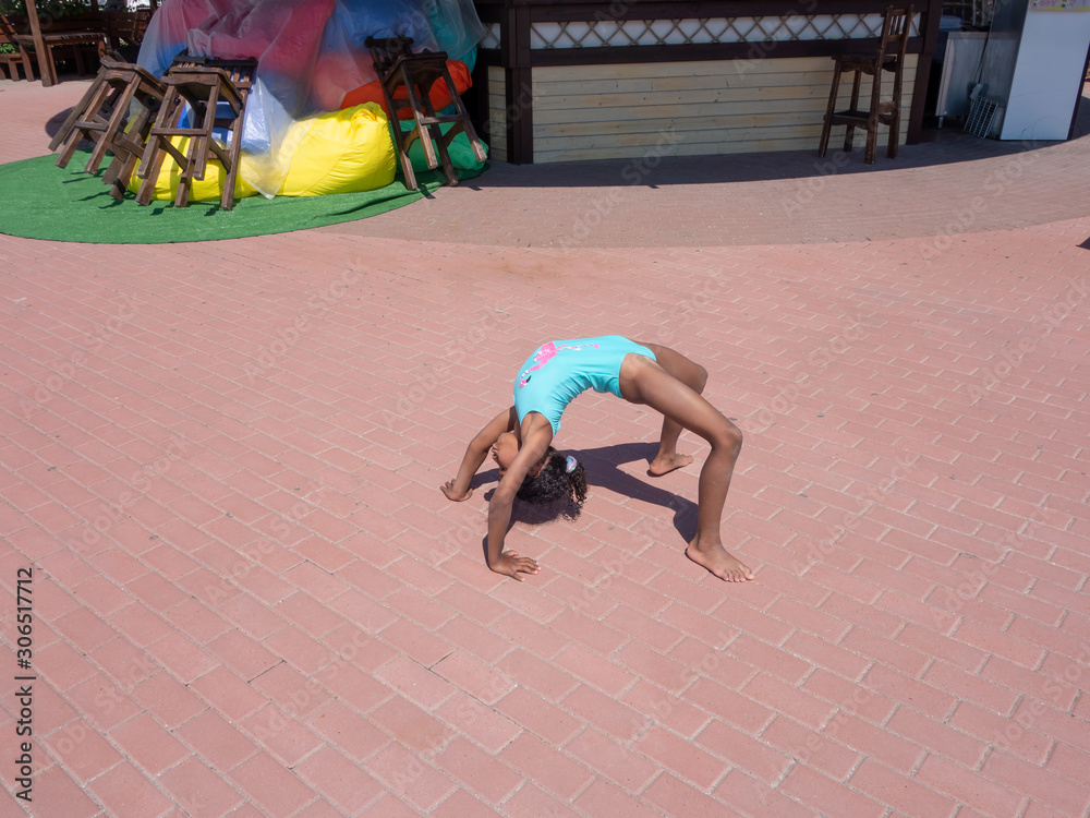 Jamaican European ethnicity little girl in a blue swimsuit does ...