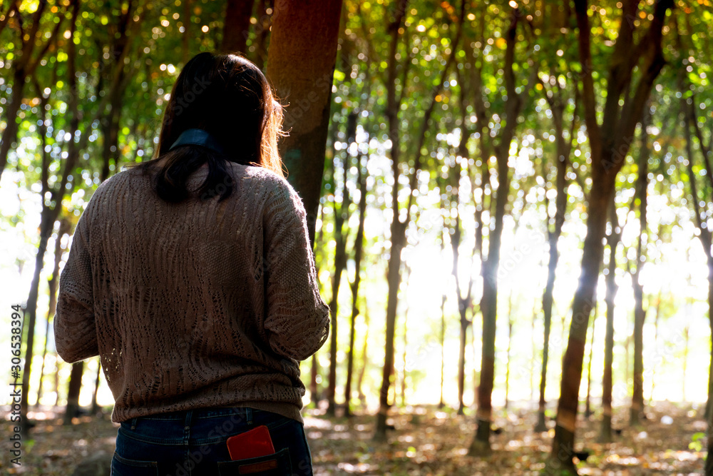 The woman stood backwards, doing something in the rubber forest with ...