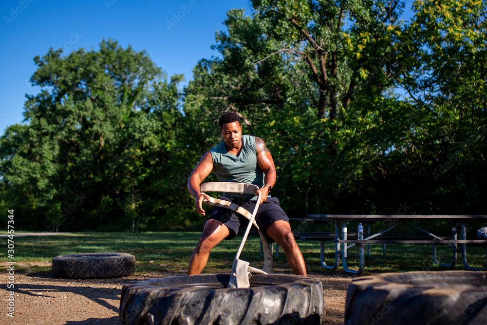 Front view of a strong athletic male pulling a heavy tire with rope ...